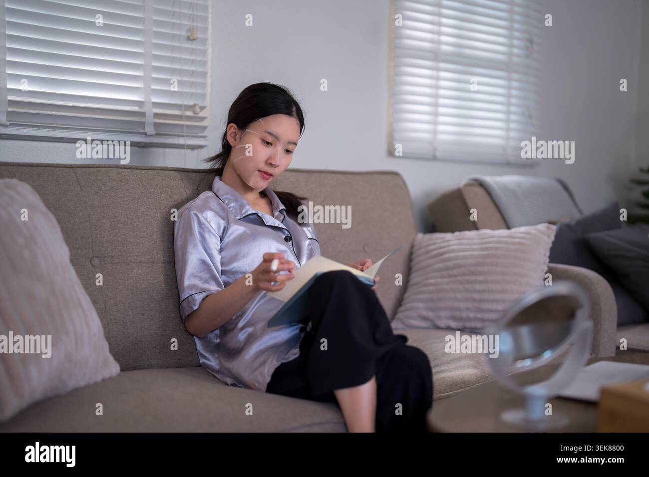 young Asian women reading book on sofa at home in comfortable living ...