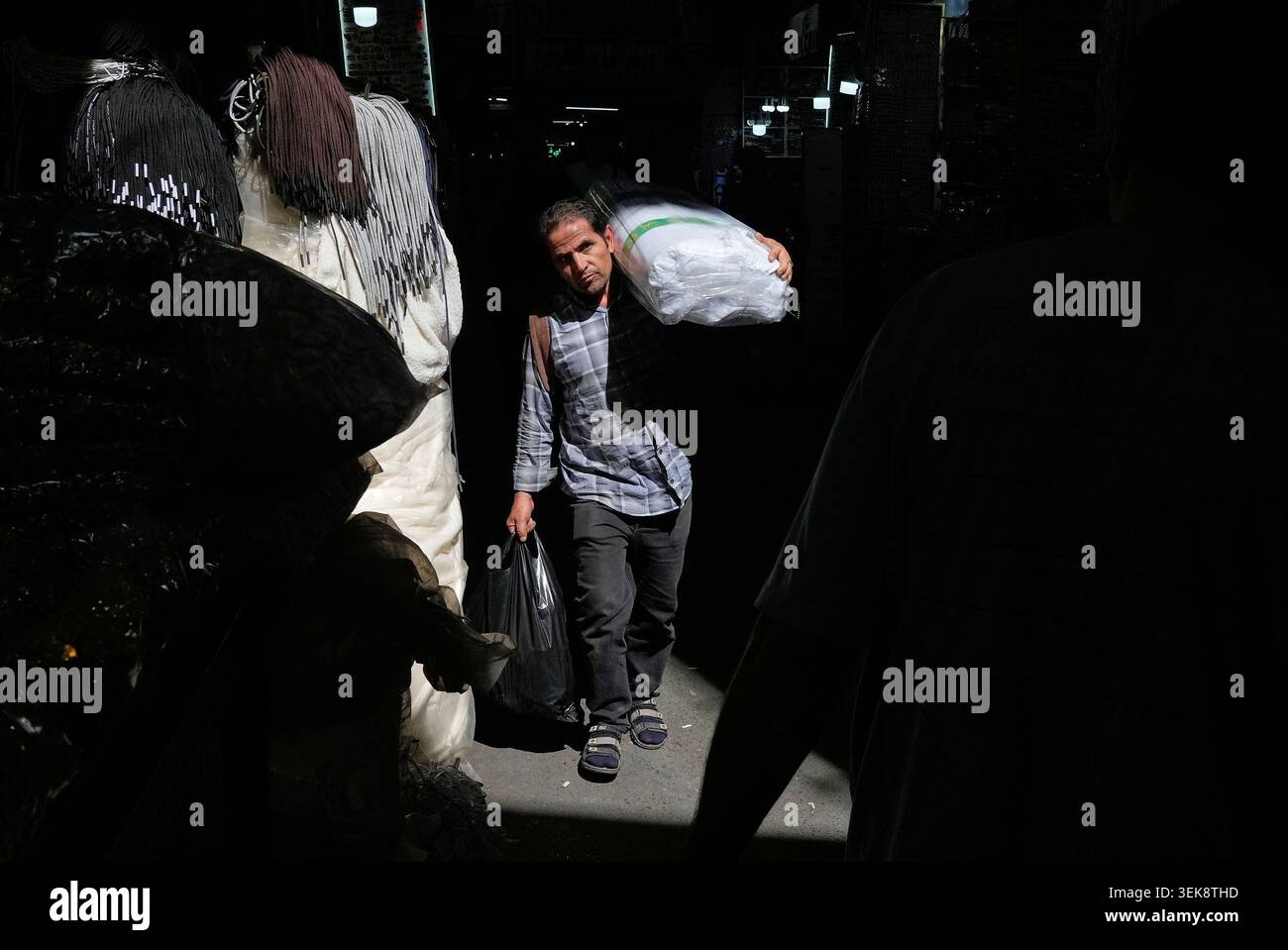 A man carries a package at Tehran's historic Grand Bazaar, Iran, Monday ...