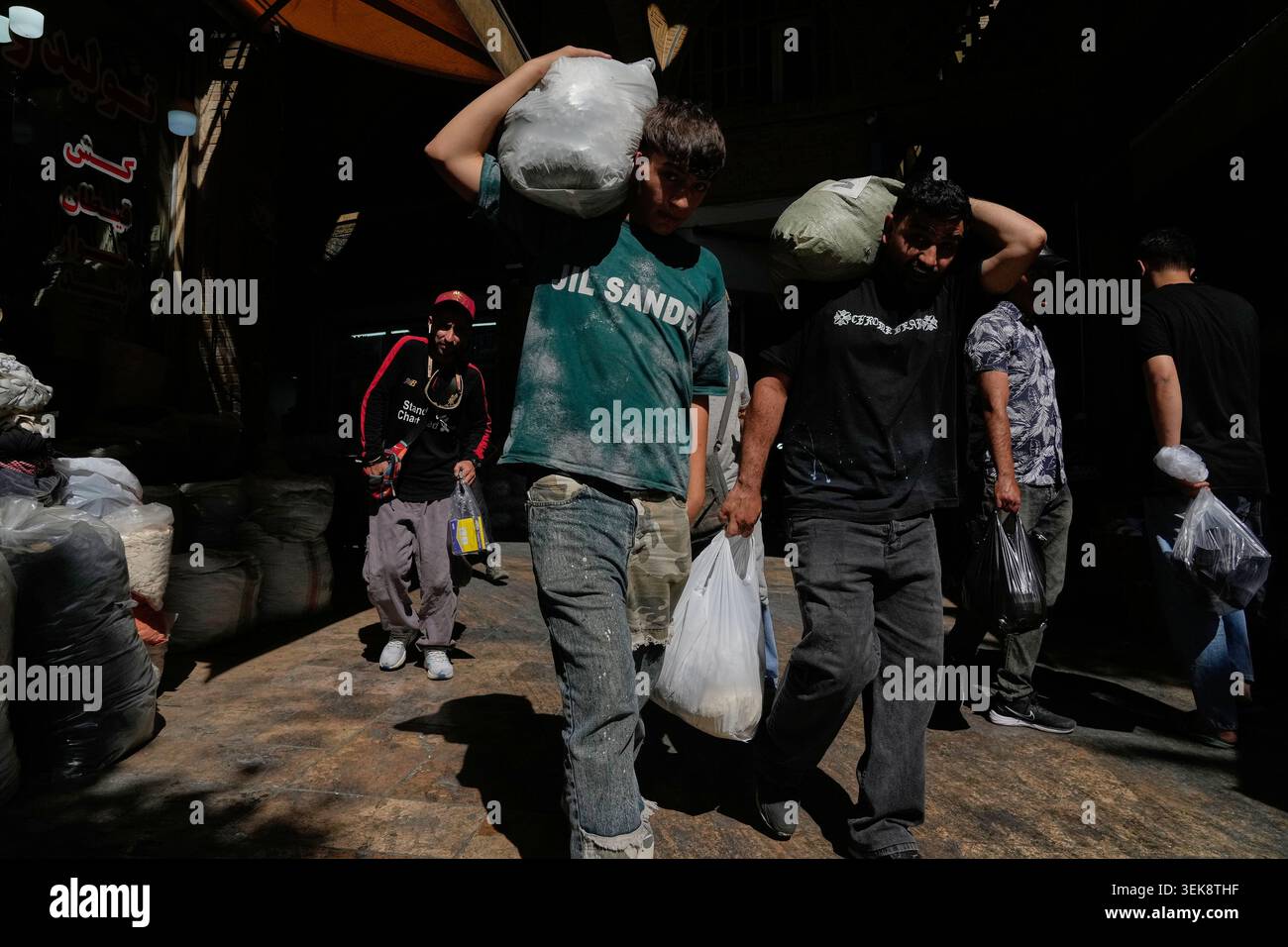 People carry packages at Tehran's historic Grand Bazaar, Iran, Monday ...