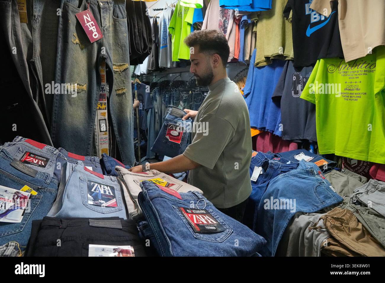 A shopkeeper arranges pants at his shop at Tehran's historic Grand ...