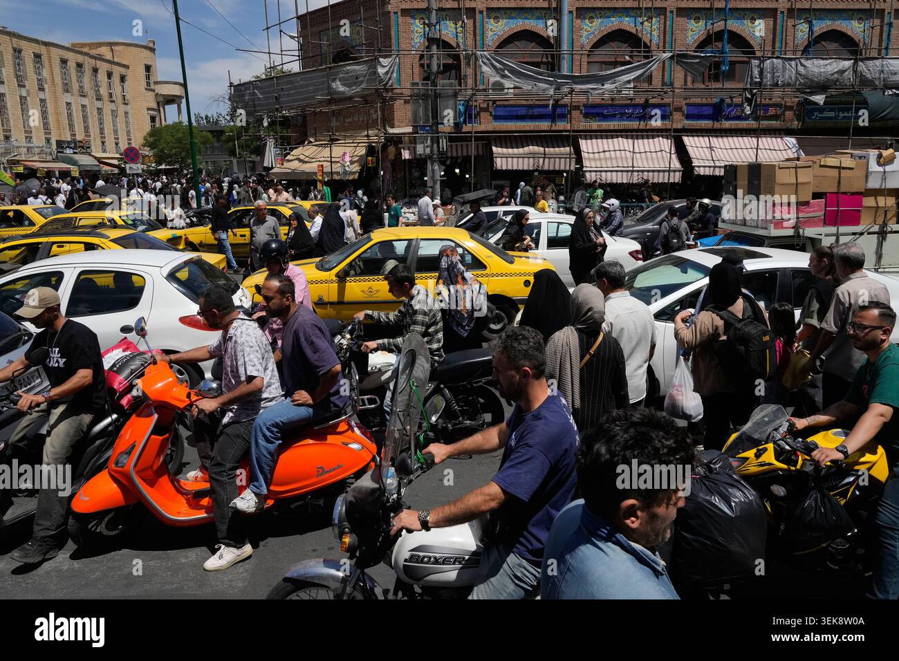 Pedestrians and vehicles cross an intersection around Tehran's historic ...