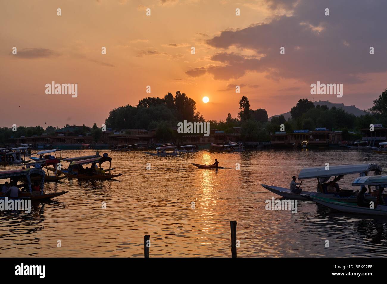 A Kashmiri man selling snacks to tourists from a boat, rows across Dal ...
