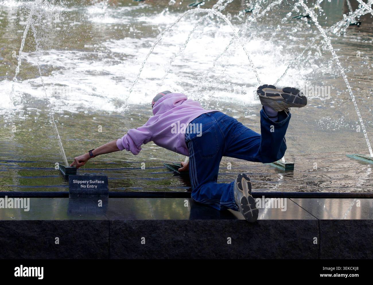 A child reaches to touch the water from a fountain at the entrance to ...