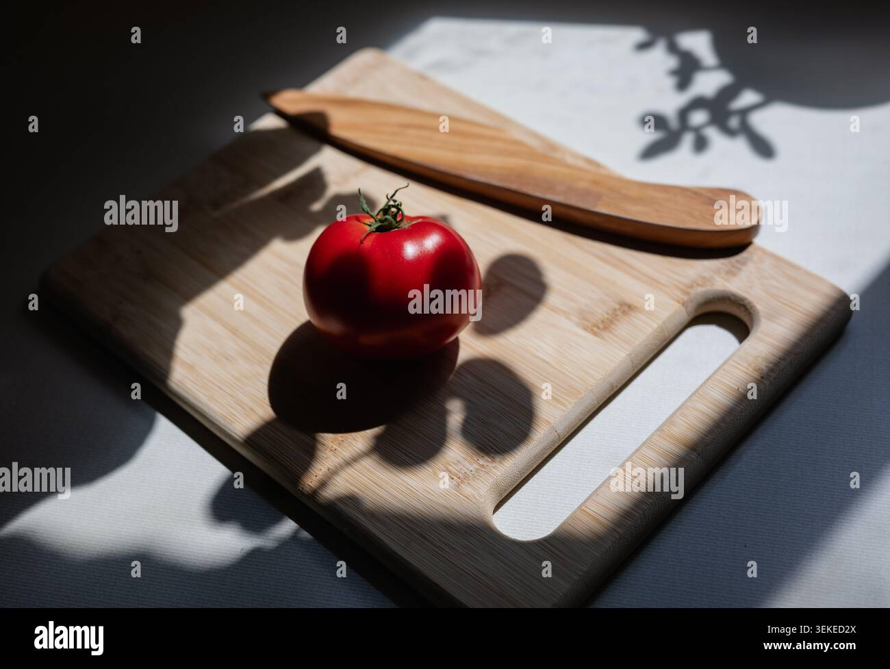 Fresh Tomato on Wooden Cutting Board with Prominent Shadows and Knife ...