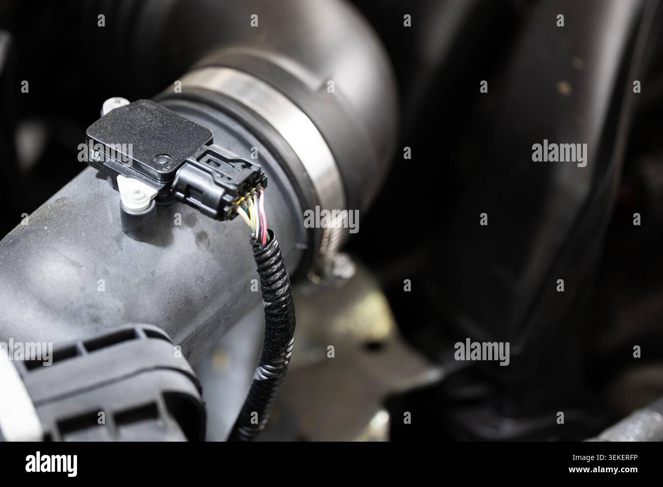 Close-up of a black MAF sensor mounted on a vehicle air intake pipe ...