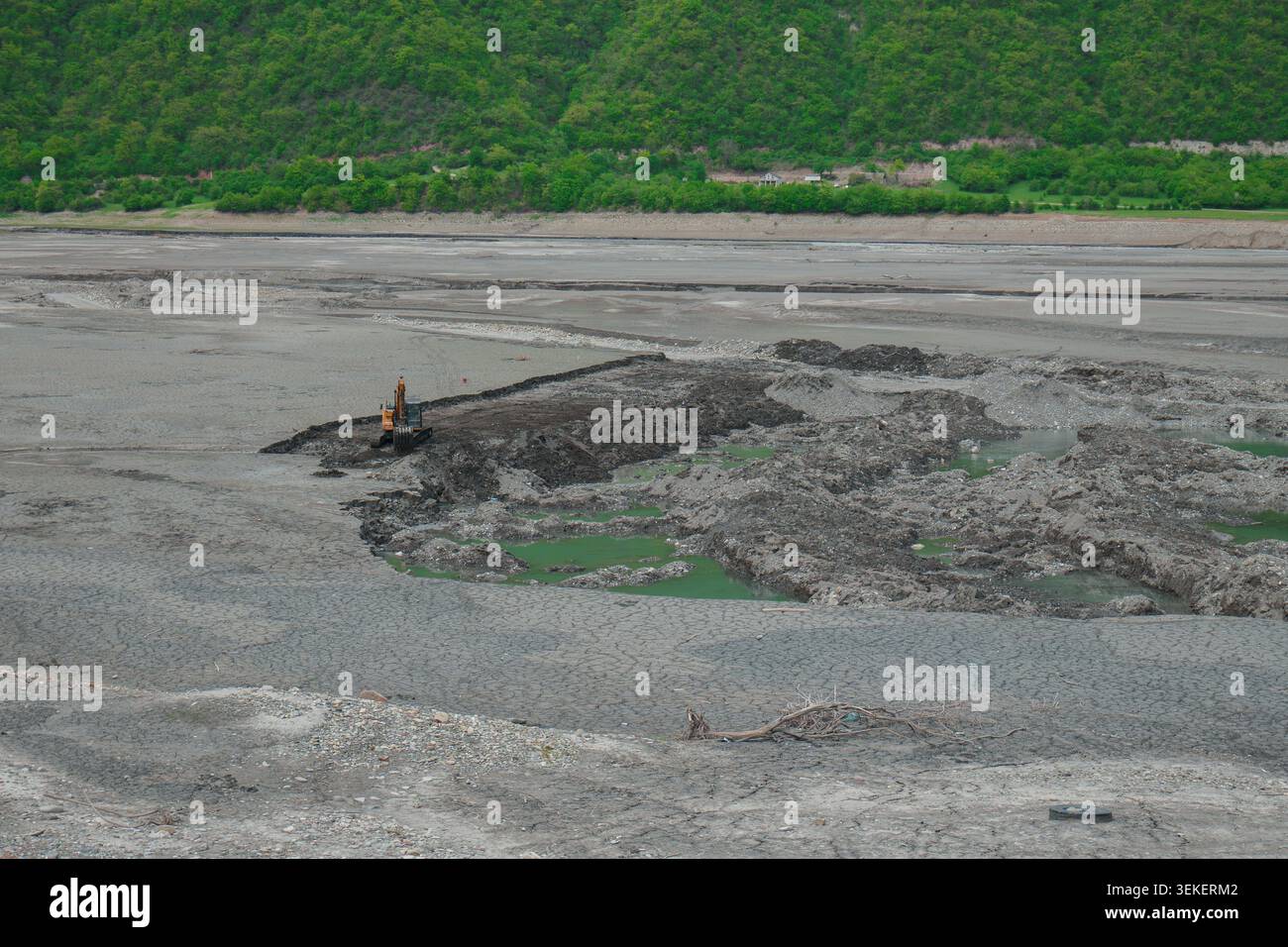 Industrial excavator digging in a dry, cracked earth landscape with ...