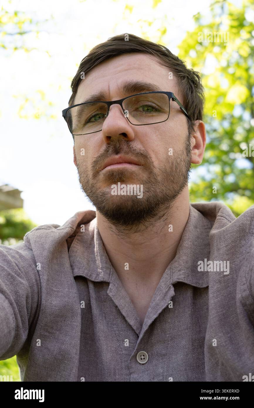A man with short brown hair, glasses, and a beard takes a close-up ...