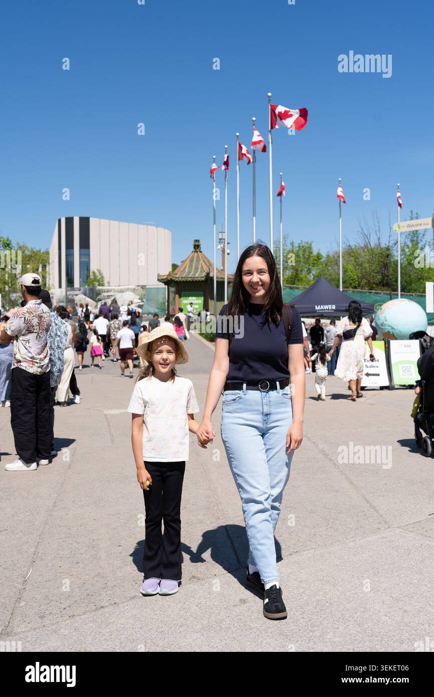A woman and a young girl holding hands and smiling at an outdoor event ...