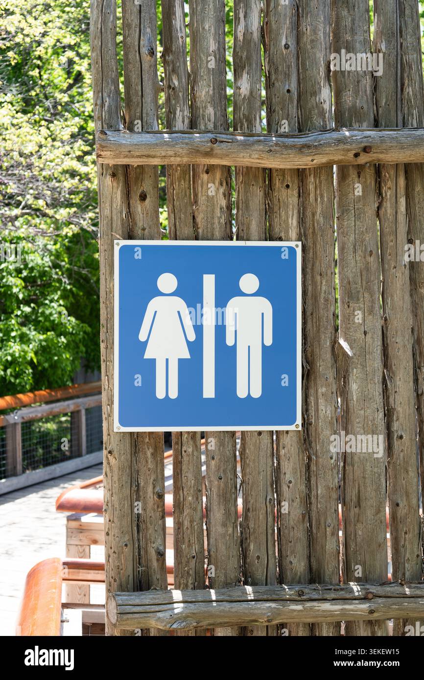 A blue restroom sign with male and female symbols is mounted on a ...