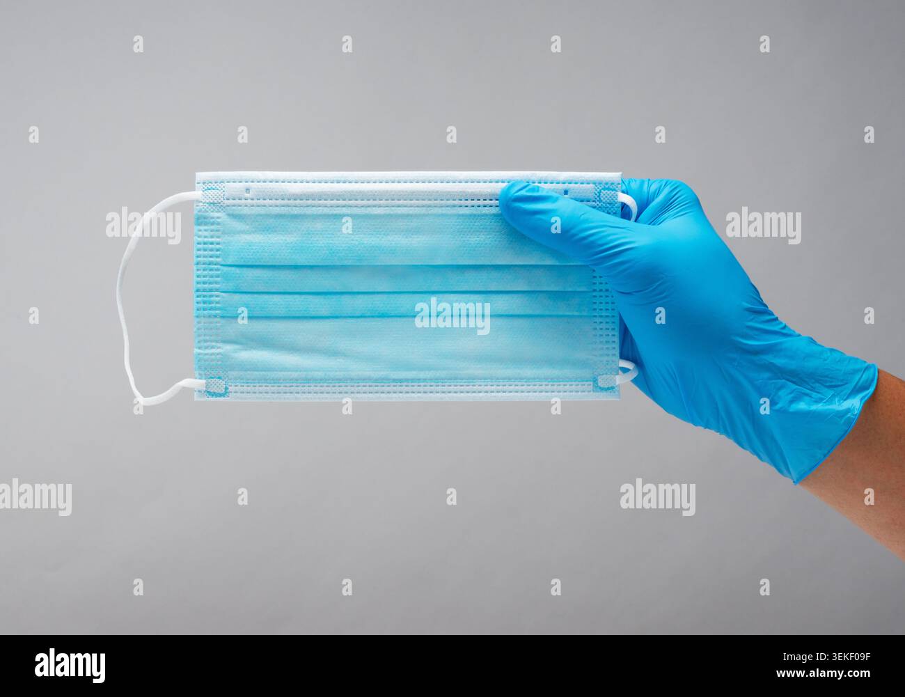 Gloved Hand Holding Blue Disposable Surgical Face Mask on Gray ...