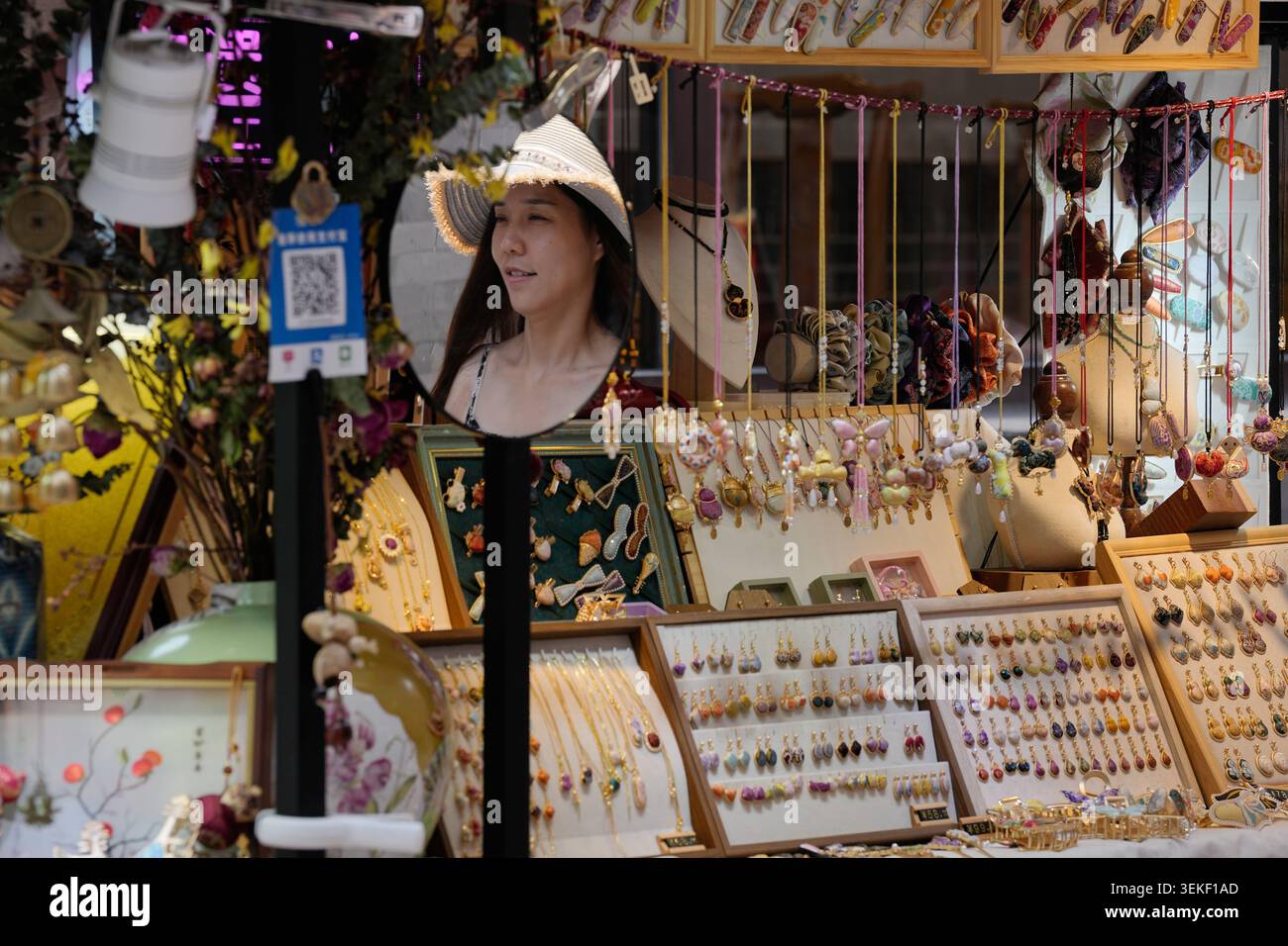 A woman is reflected on a mirror hang on a fashion accessories store in ...