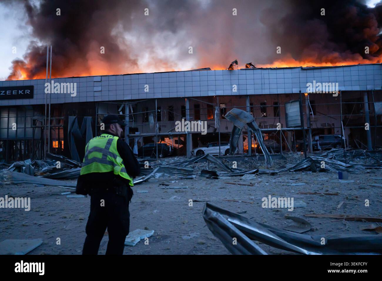 Ukrainian police officer in front of a burning building after a large ...