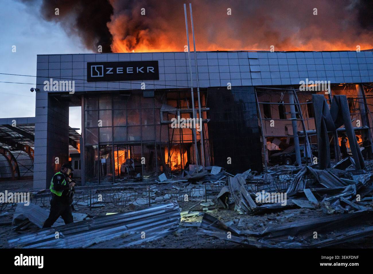 Ukrainian police officer walks pass by a burning building after a large ...