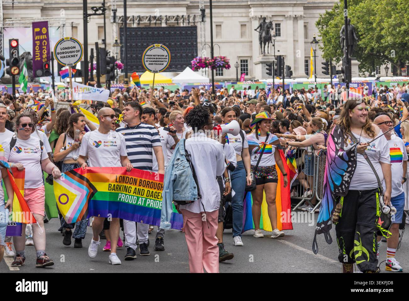 Diverse crowd marching at London Pride parade with rainbow flags ...