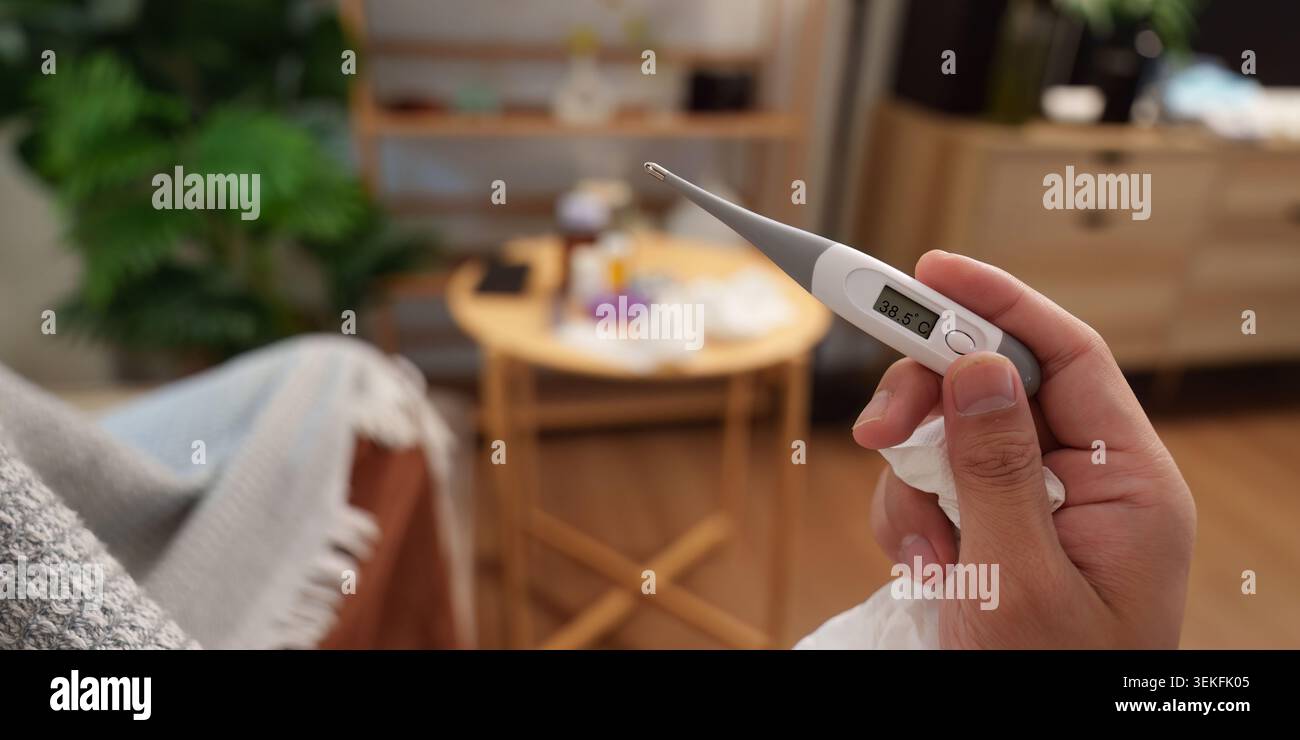 Hand holding thermometer showing fever temperature at home Stock Photo ...