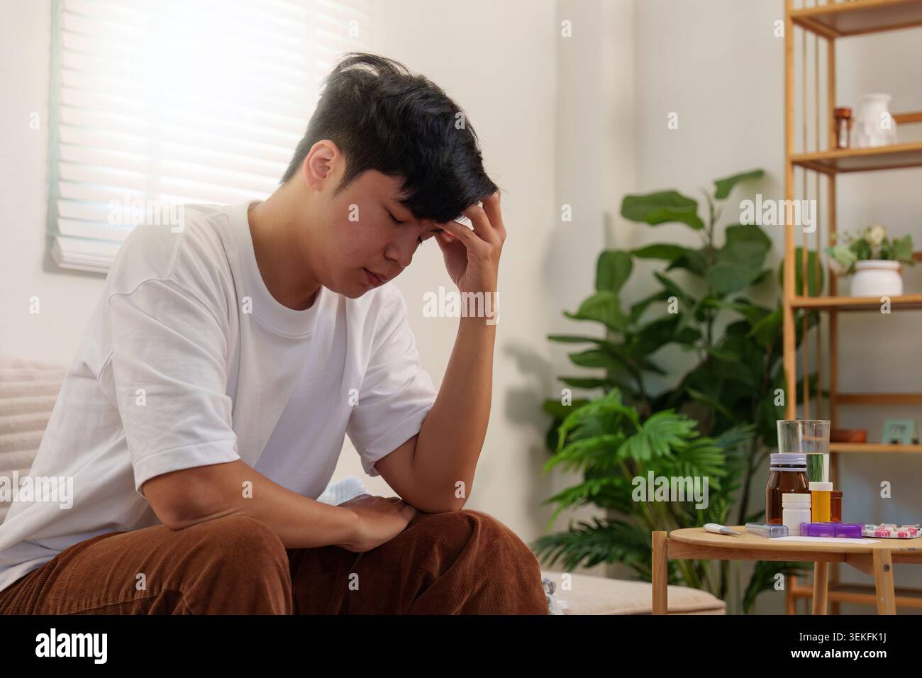 Asian man holding head with headache feeling unwell at home Stock Photo ...