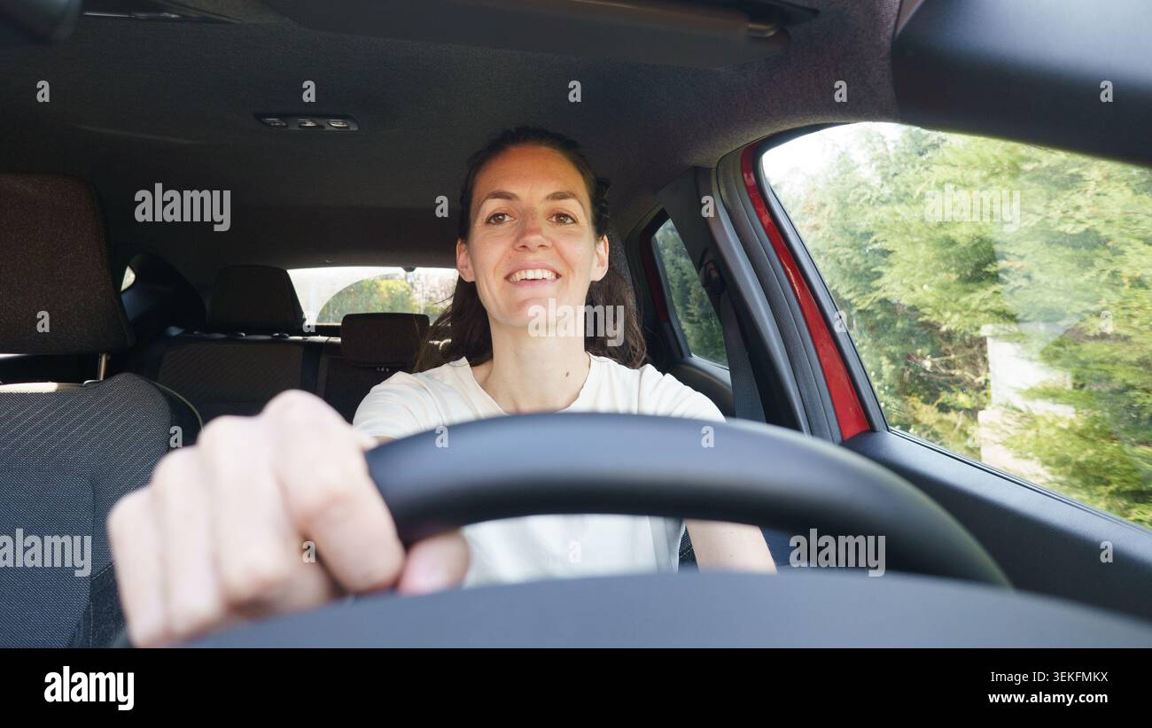 Young woman driving car looking at camera with a happy expression Stock ...