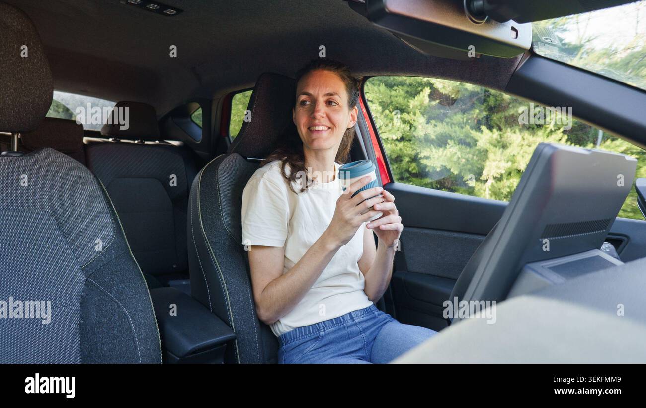 Woman smiling, holding a reusable coffee cup, inside a car Stock Photo ...