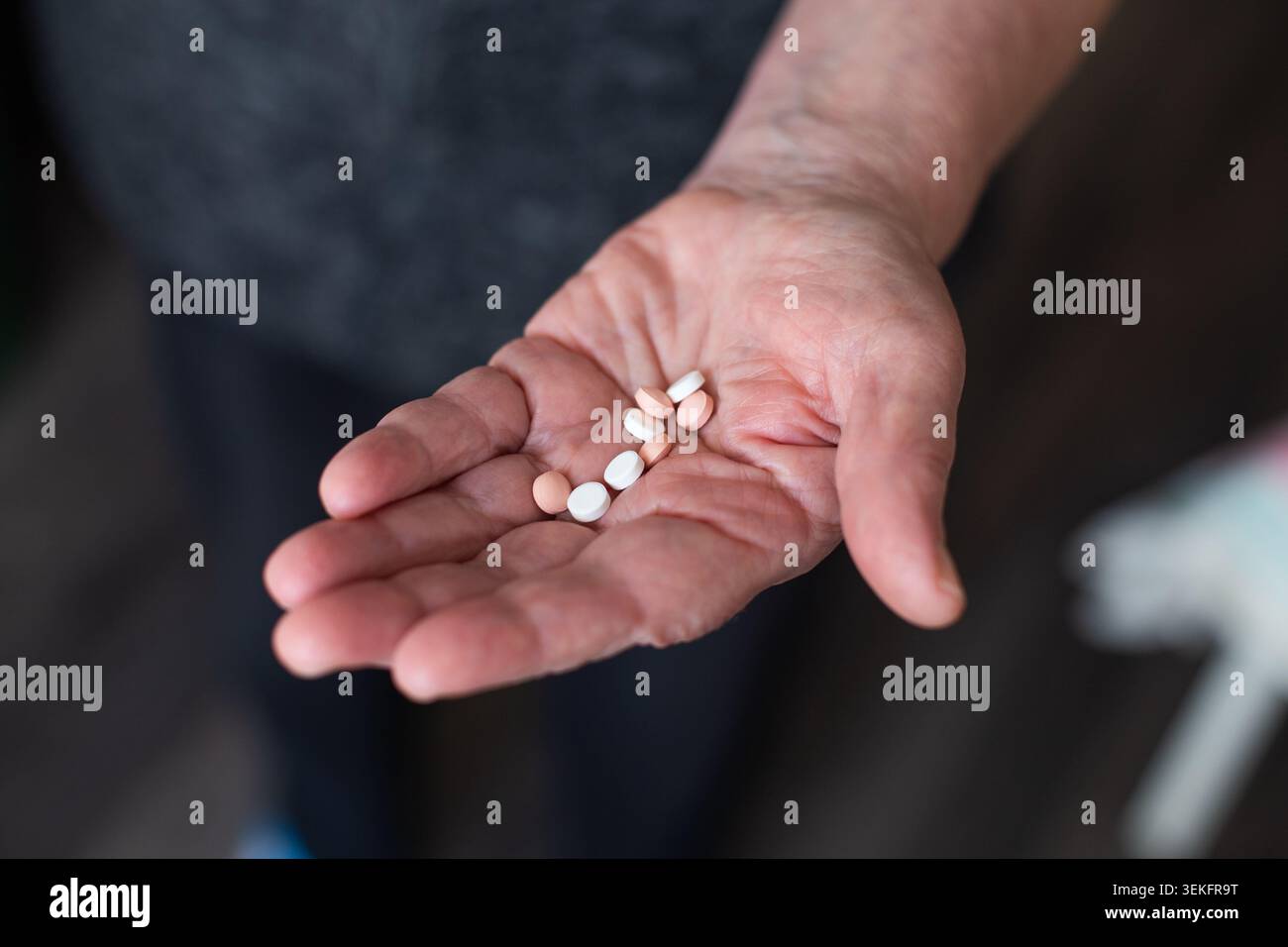 Elderly person's hand holding a small quantity of various ...