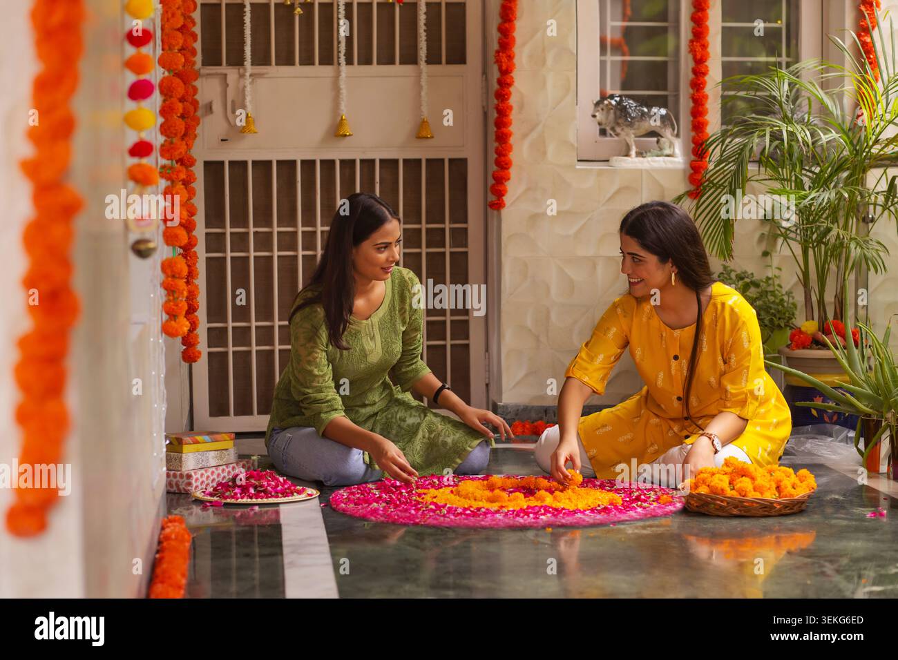 Two sisters decorating house with flowers on the occasion of Diwali ...