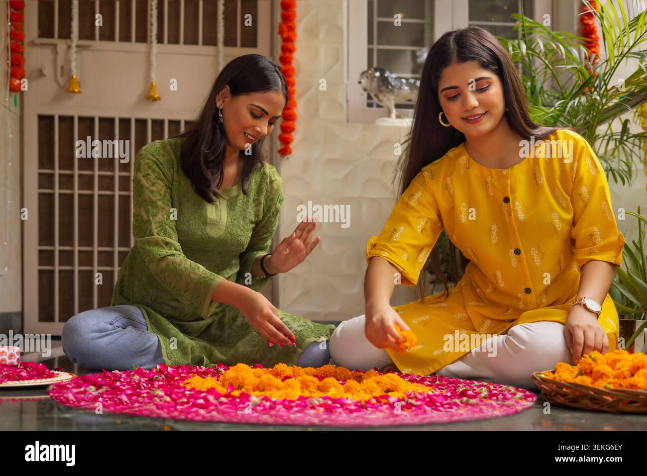 Two sisters decorating house with flowers on the occasion of Diwali ...