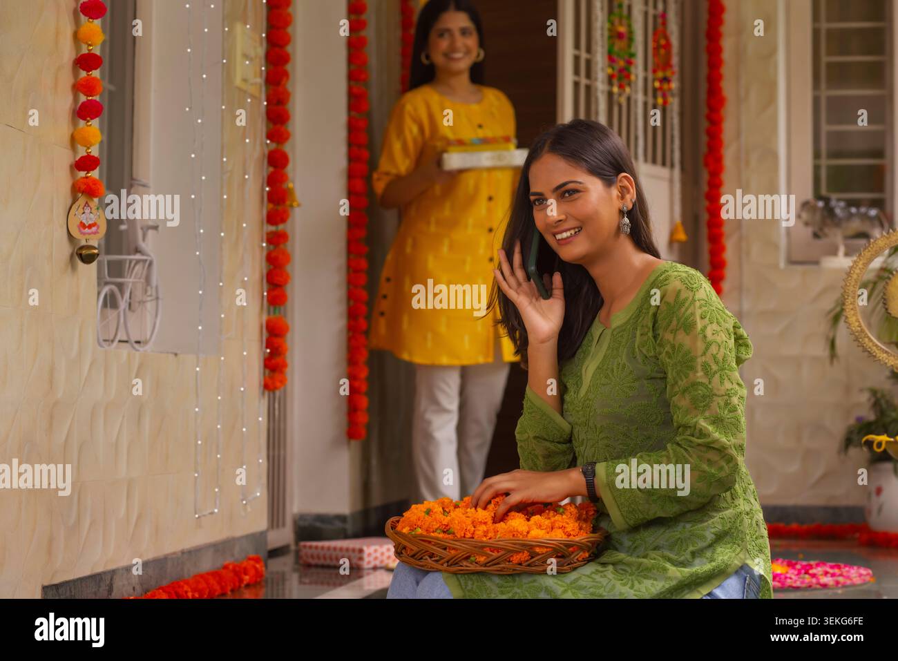 Young woman talking on mobile phone while decorating house with flower ...