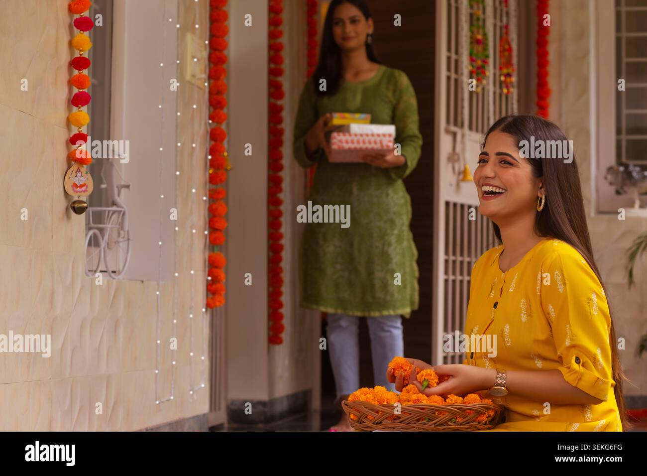 Young woman decorating house with flower on the occasion of Diwali ...
