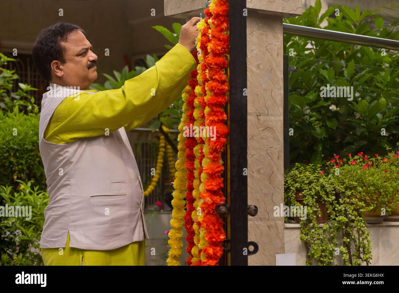 Man in traditional outfit decorating entrance gate with flower on the ...