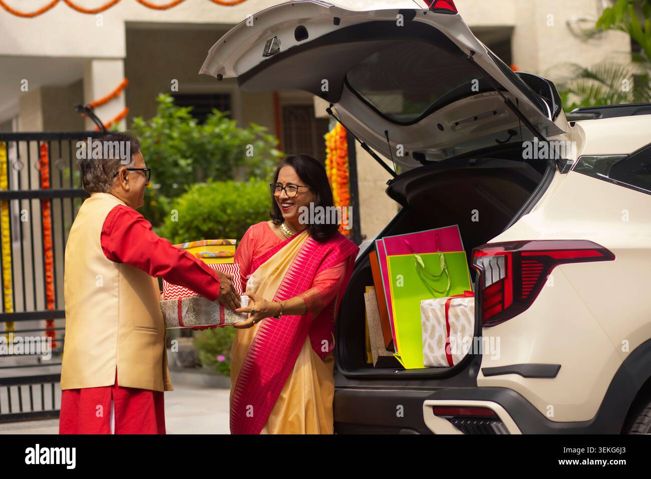 Senior couple unloading Diwali gifts from car trunk after shopping ...