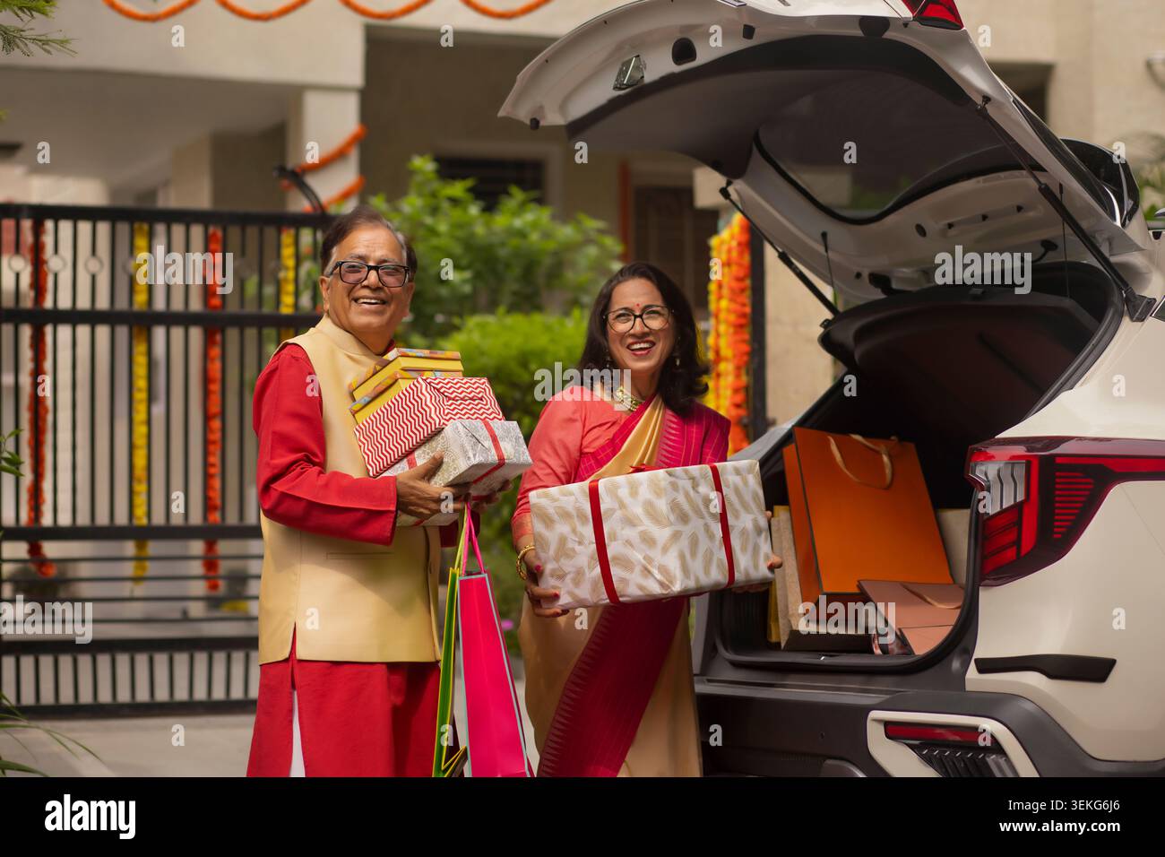 Senior couple unloading Diwali gifts from car trunk after shopping ...