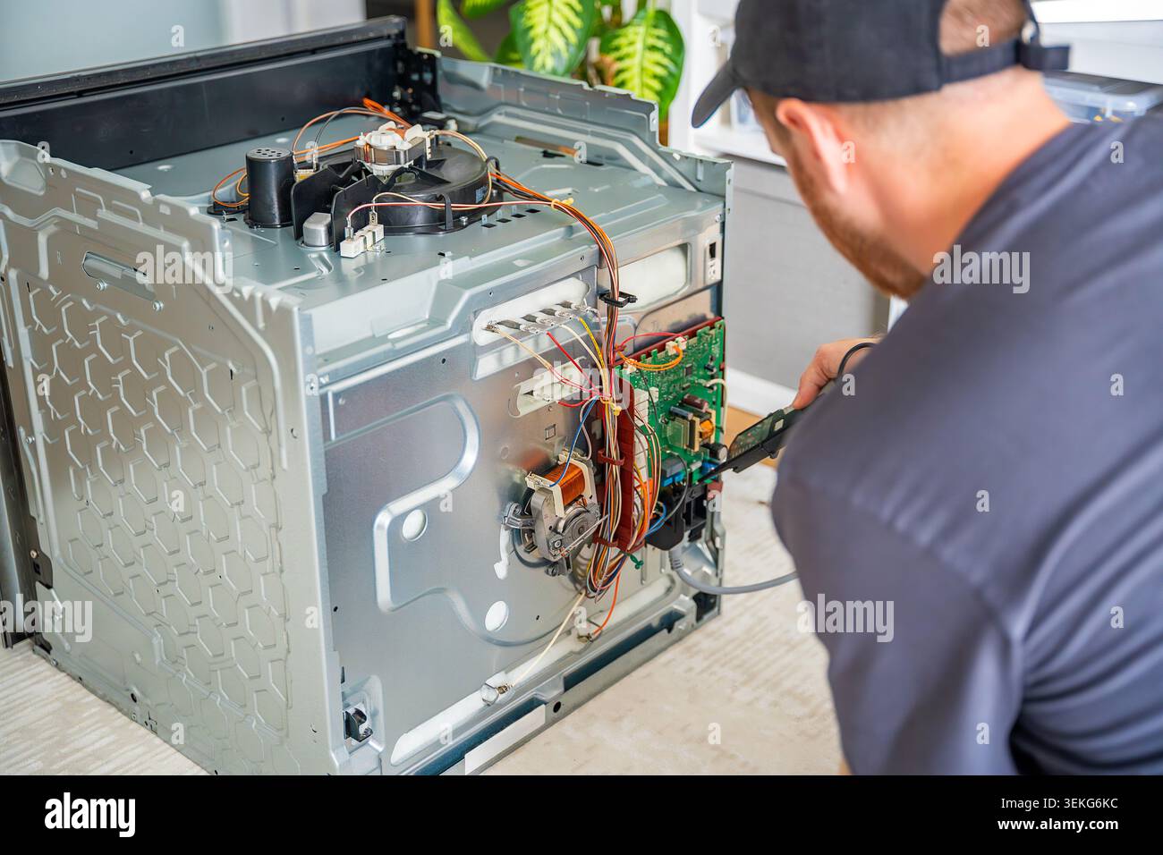 Technician testing electronic components and wiring inside disassembled ...