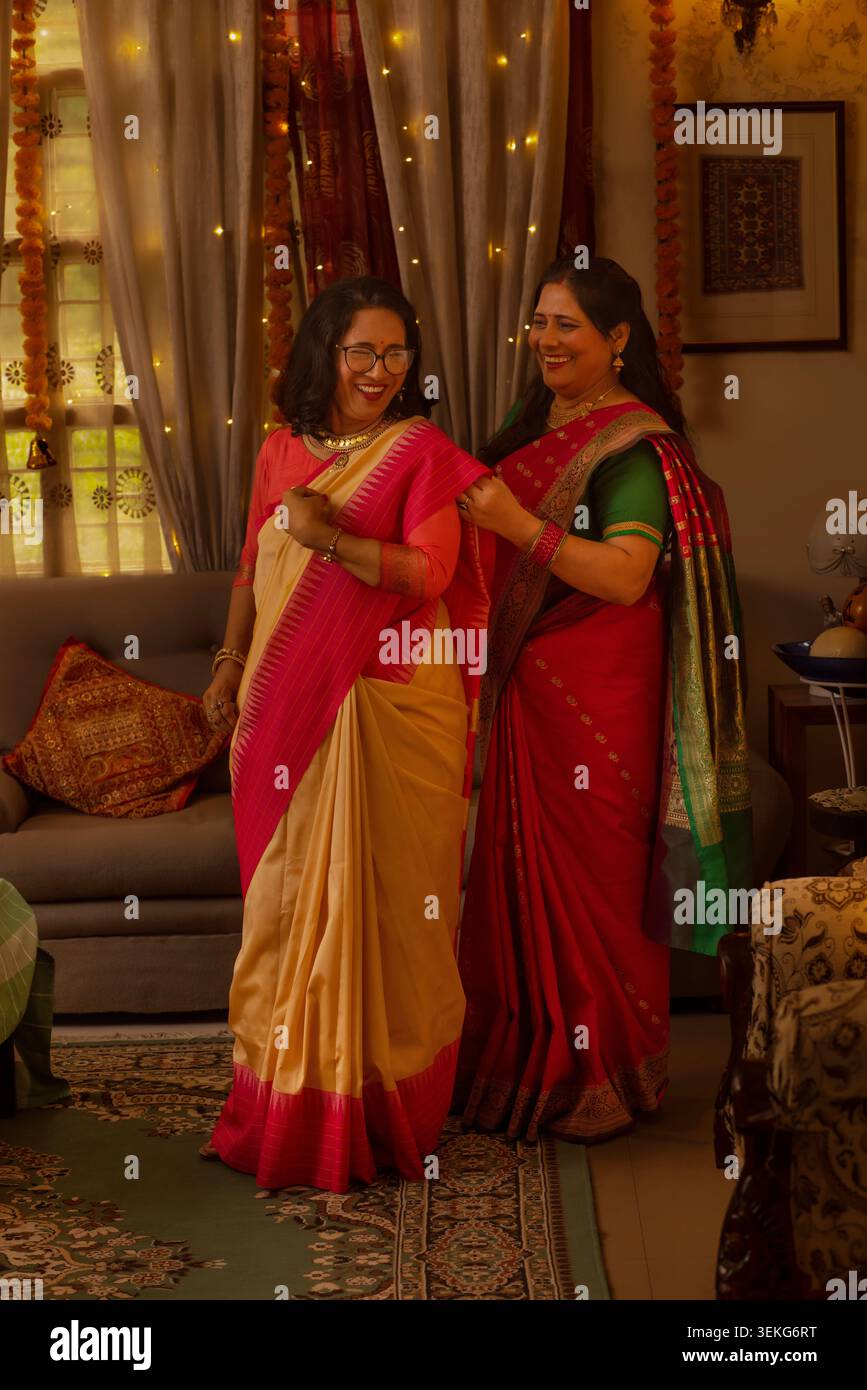 Woman helping her mother-in-law to wear saree on Diwali Stock Photo - Alamy