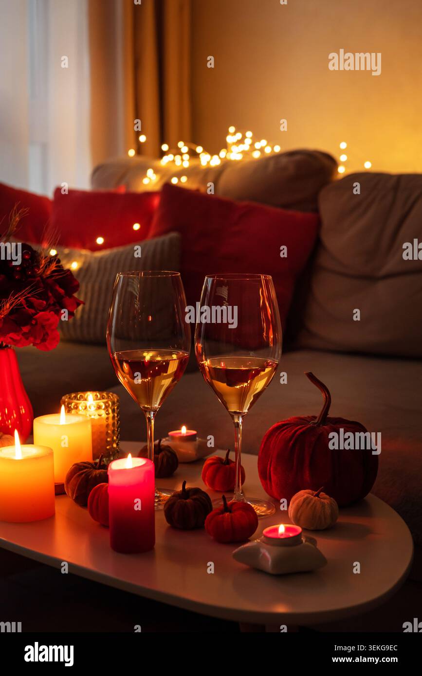 Cozy evening scene with candles, white wine glasses and warm candle ...
