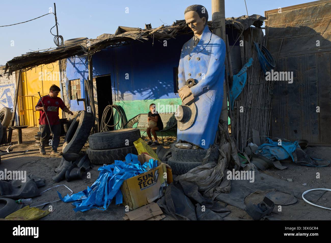 A man works at a tire shop adorned with a statue of Peruvian poet Cesar ...