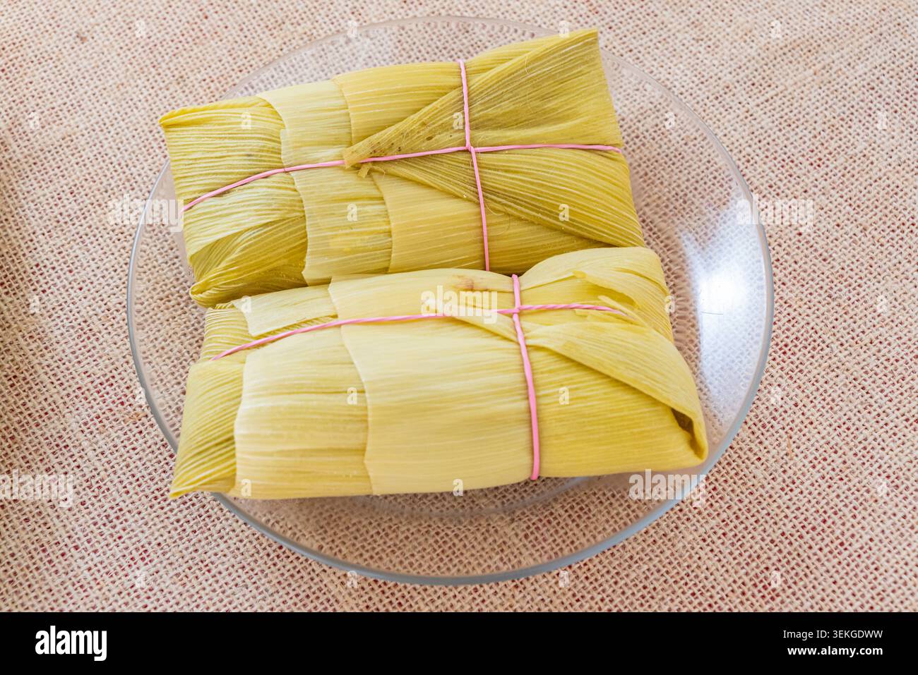Studio shot featuring two pamonhas neatly wrapped in pale yellow corn ...