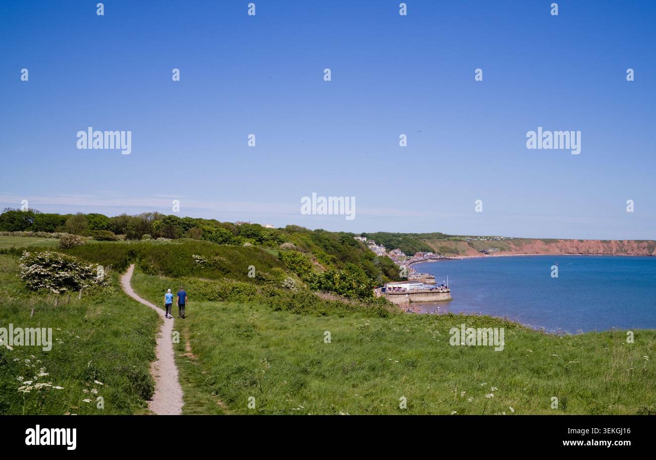 An older couple walking on the coastal footpath above Filey beach Stock ...