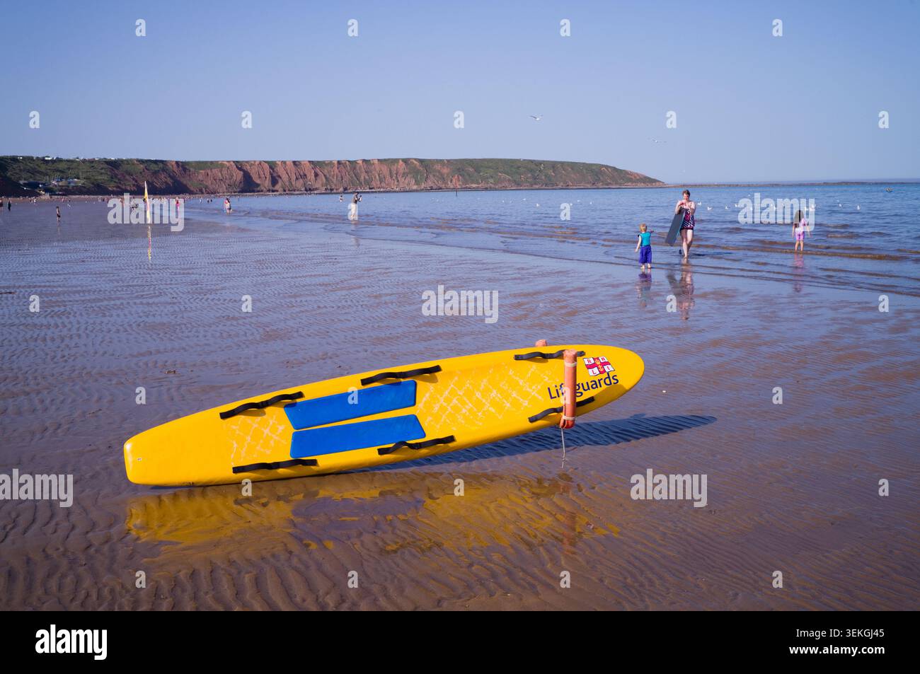 Bathers in the sea next to a RNLI surfboard at Filey beach, North ...