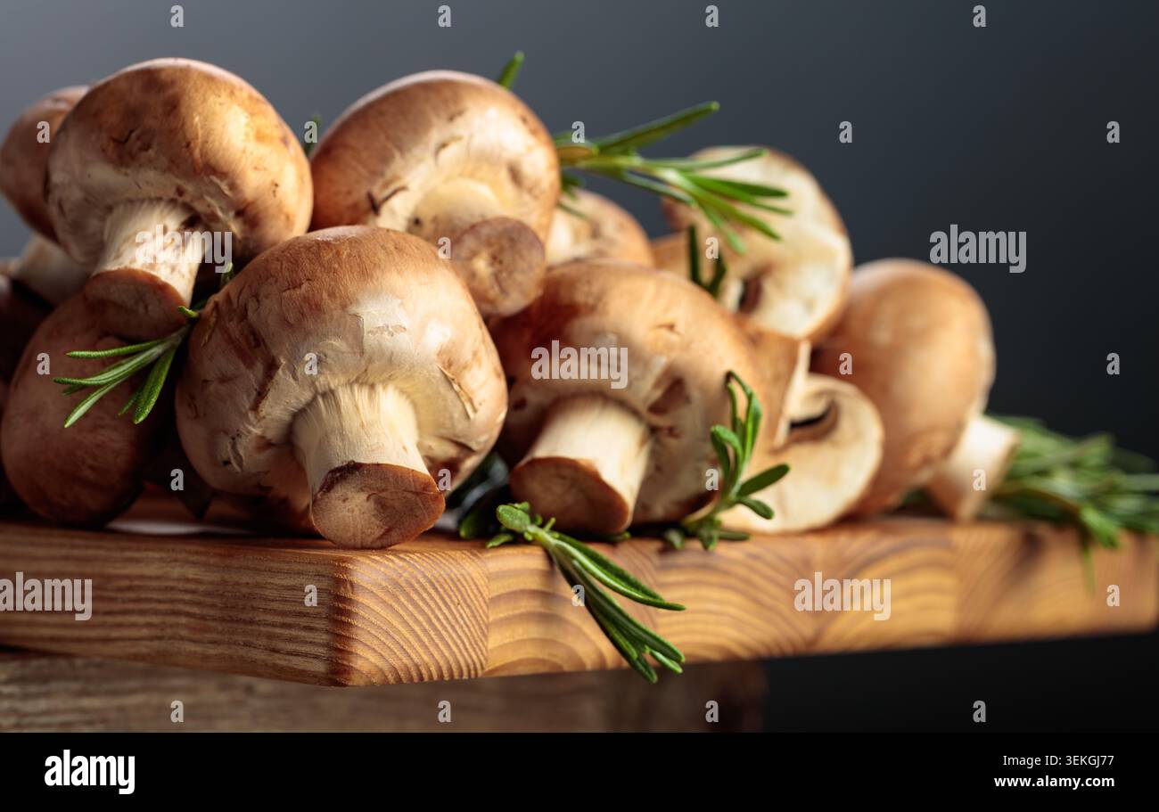Mushrooms on a wooden cutting board. Champignon with rosemary. Copy ...