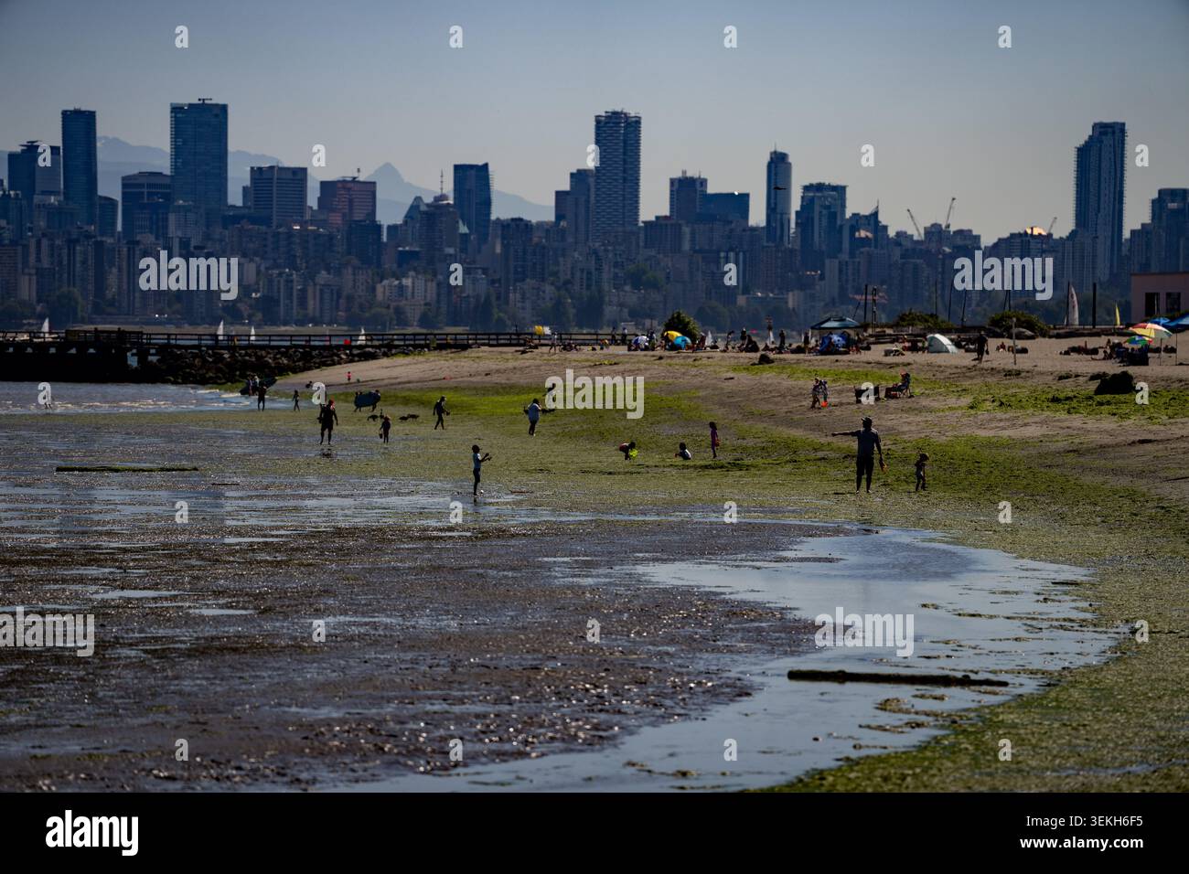 People walk on the beach during low tide in Vancouver, B.C., Sunday ...