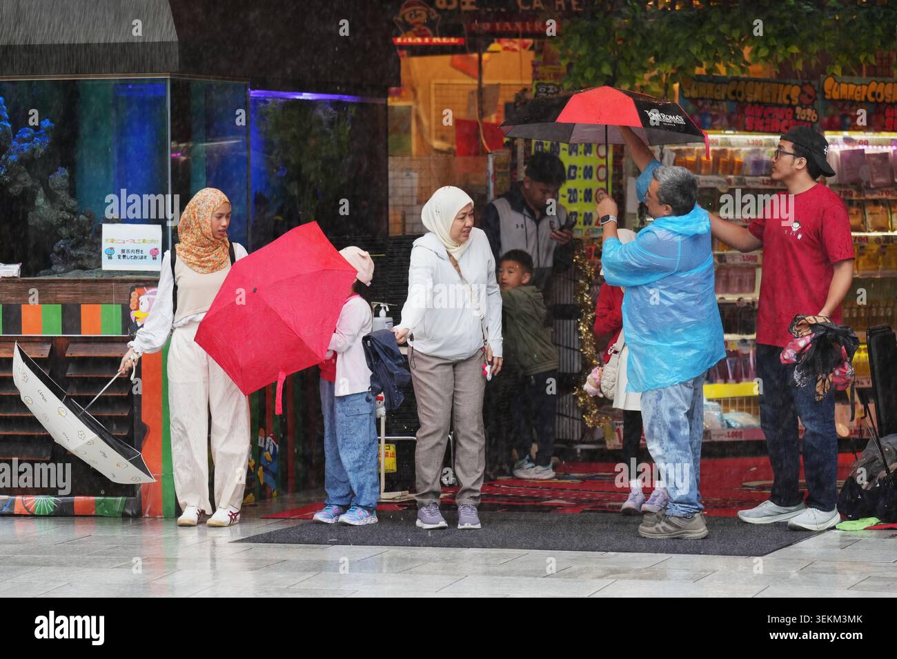 People fold umbrellas to get into a store during a rain in Tokyo ...