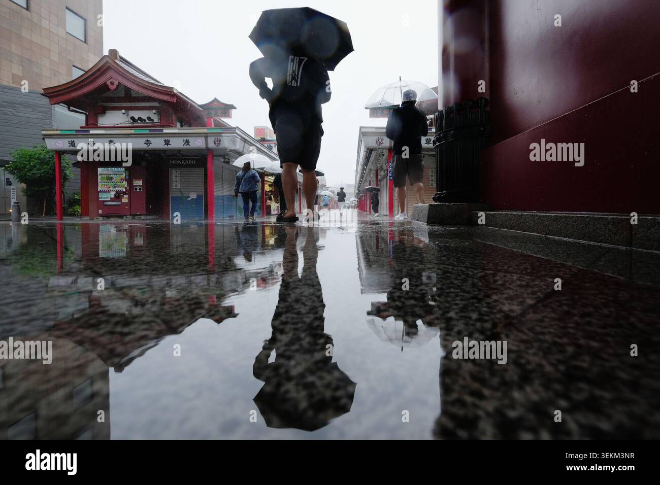 A man stops to take shelter from a rain in Tokyo, Wednesday, June 3 ...