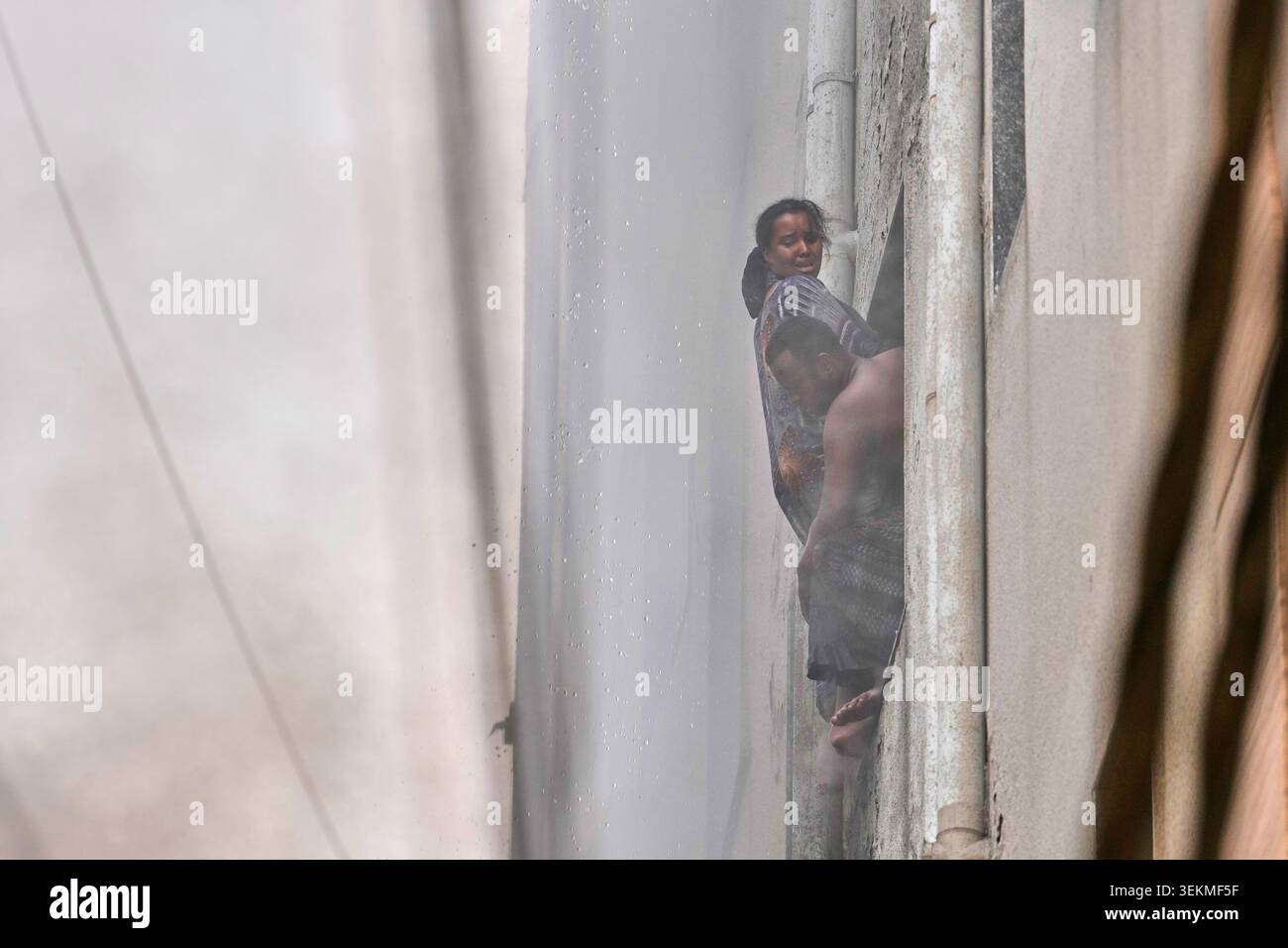 A family of foreign nationals hangs from a hotel window as fire engulfs ...