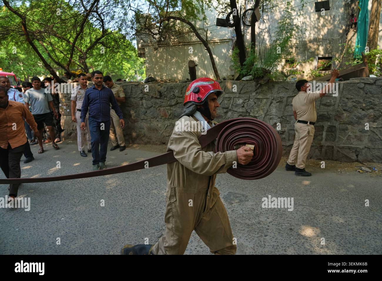 A firefighter runs with a hose toward a hotel fire in New Delhi, India ...