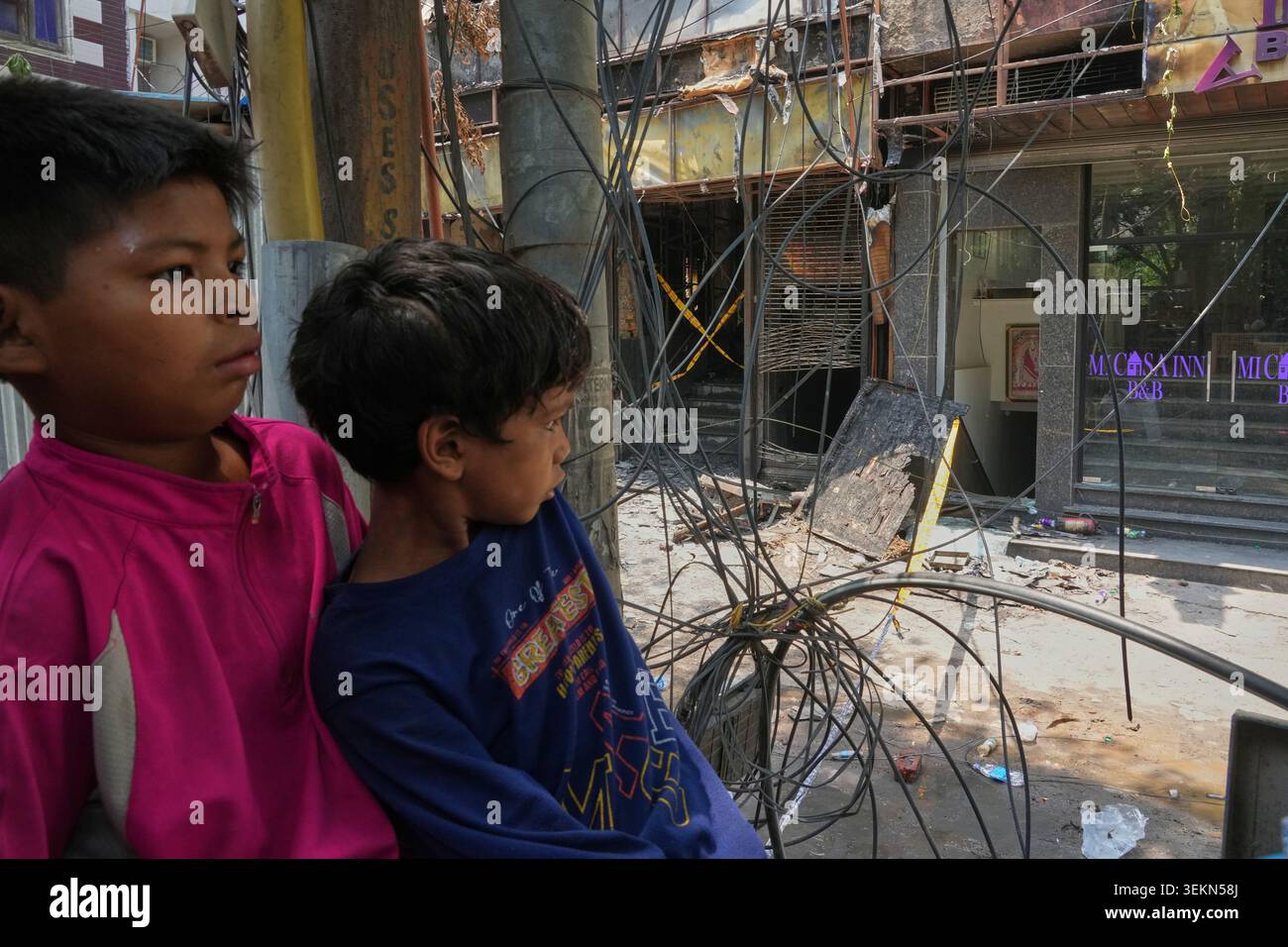 Children look at a restaurant and hotel building that caught fire early ...