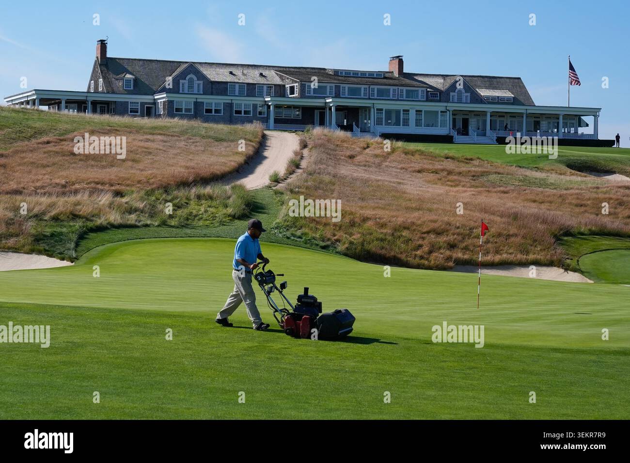 FILE - A man works on the 18th green in front of the clubhouse at ...