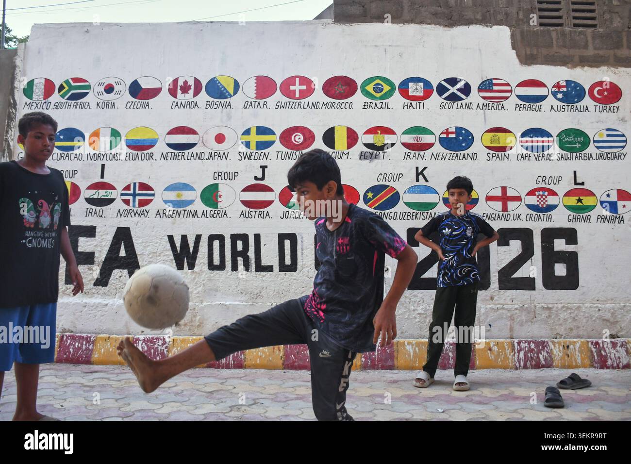 Children play soccer next to a wall painted with the flags of countries ...