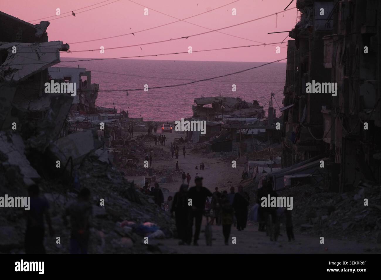 Palestinians walk between destroyed buildings in Gaza City, Wednesday ...