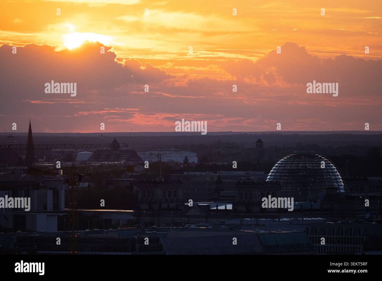 03 June 2026, Berlin: The sun sets behind clouds with the Bundestag in ...
