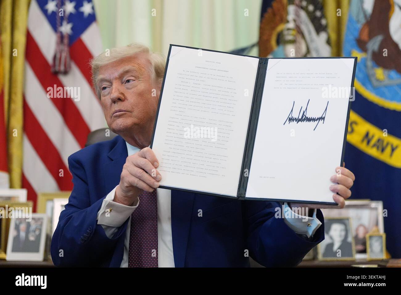 President Donald Trump holds up an executive order in the Oval Office ...