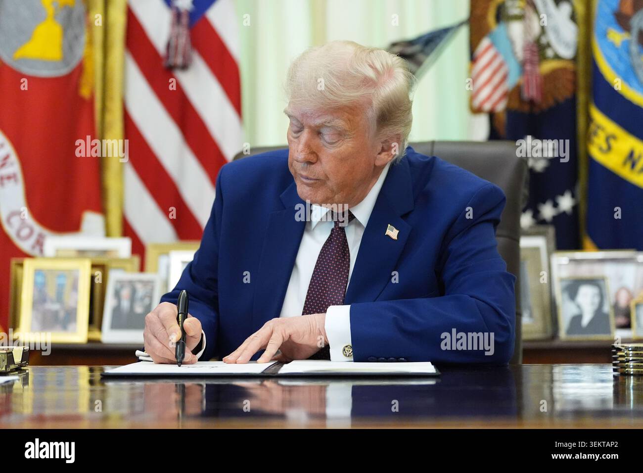 President Donald Trump signs an executive order in the Oval Office of ...
